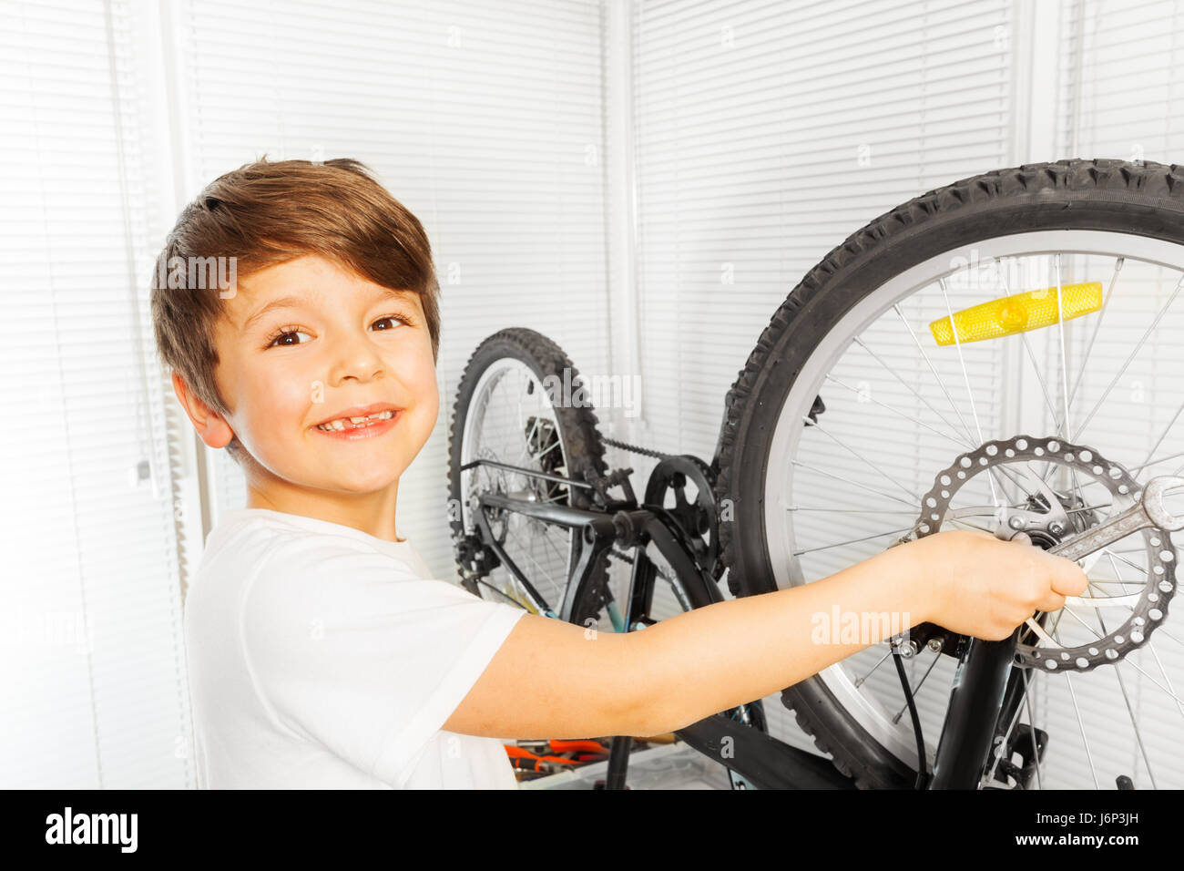 Close-up portrait of happy six years old boy repairing his bicycle ...