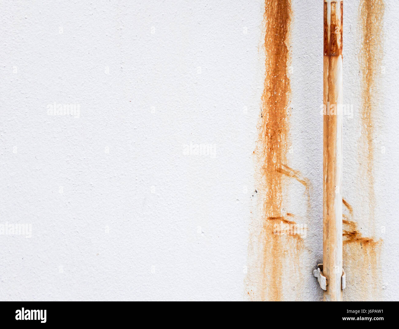 White pipe with the rusty stain on the white concrete wall in the ...