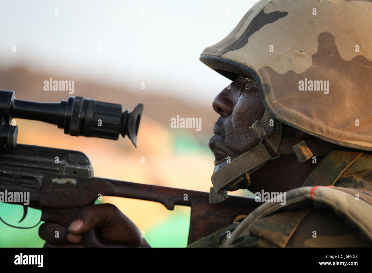This image depicts an African soldier in a combat stance, aiming a ...