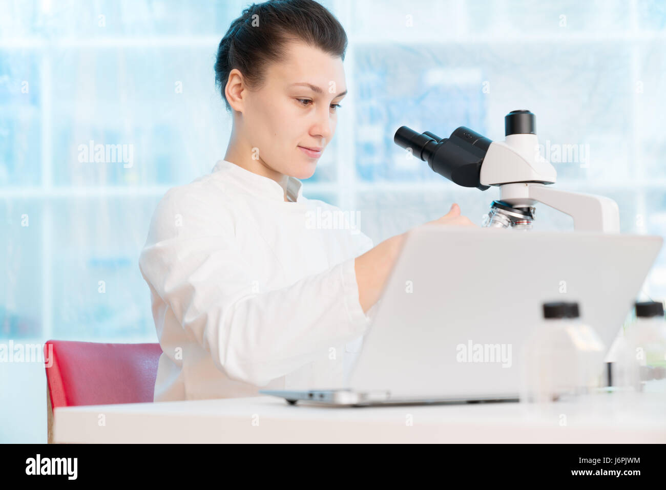 Young women work in laboratory. Microscope and notebook on table Stock ...
