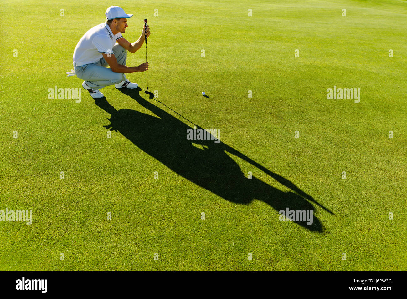Pro golf player aiming shot with club on course. male golfer check line ...