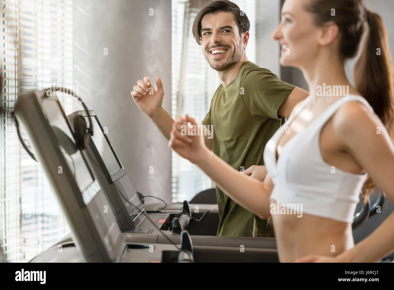 Determined young man smiling while running on treadmill during h Stock ...