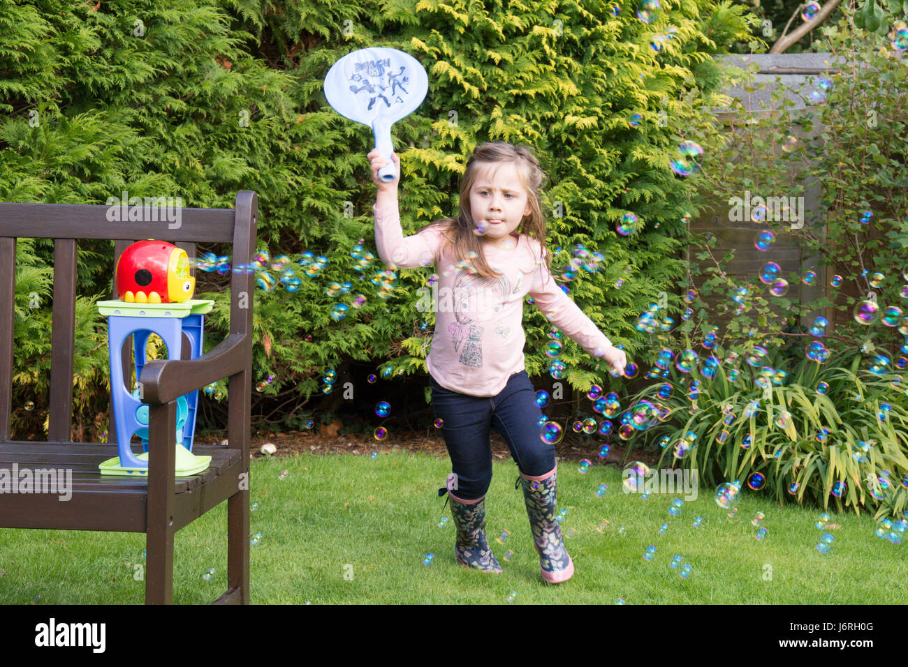 three year old girl hitting with a bat bubbles made by a bubble machine ...