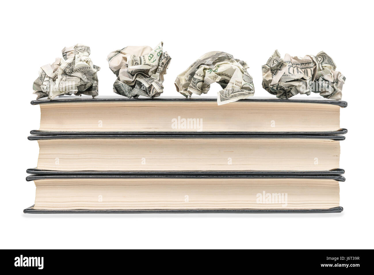 Crumpled money lying on top of a pile of closed books isolated on a ...