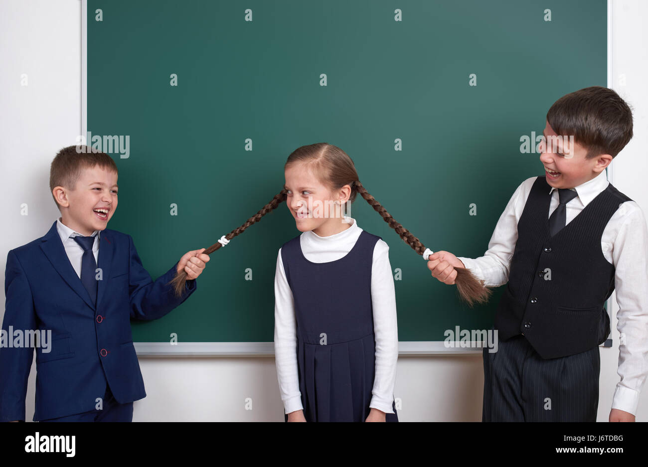 child play and having fun, boys pull the girl braids, near blank school ...