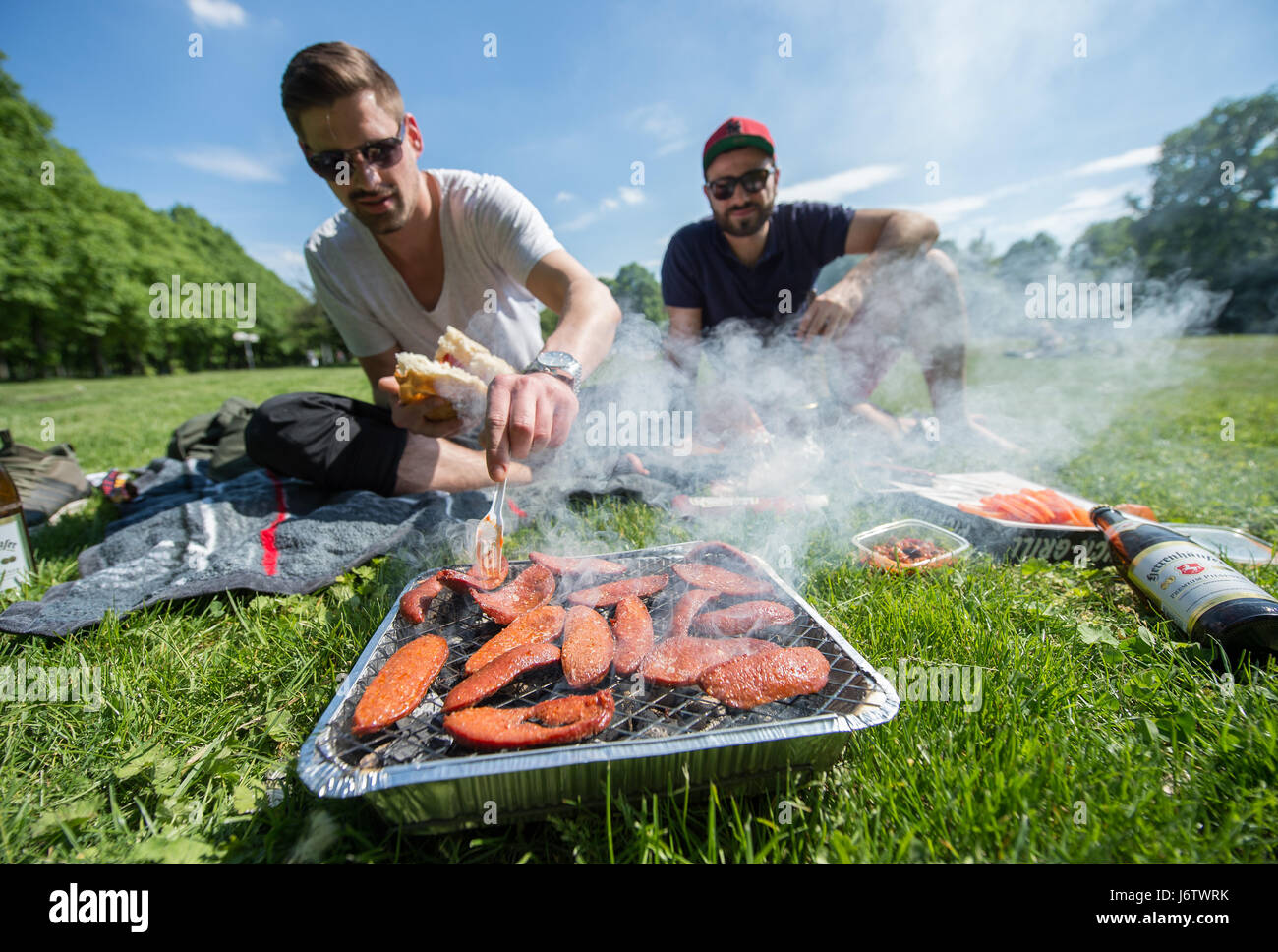 Vincent (L) and Taylan cook Turkish sujuk sausage on a grill in a park ...