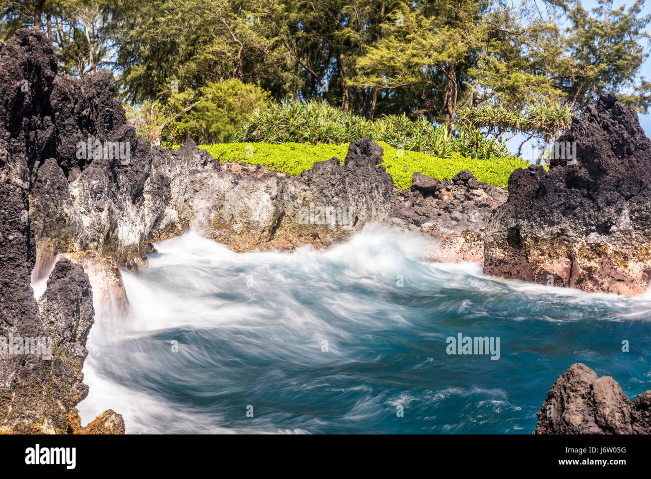 A vibrant, scenic Hawaiian cove with waves washing shore highlights the ...