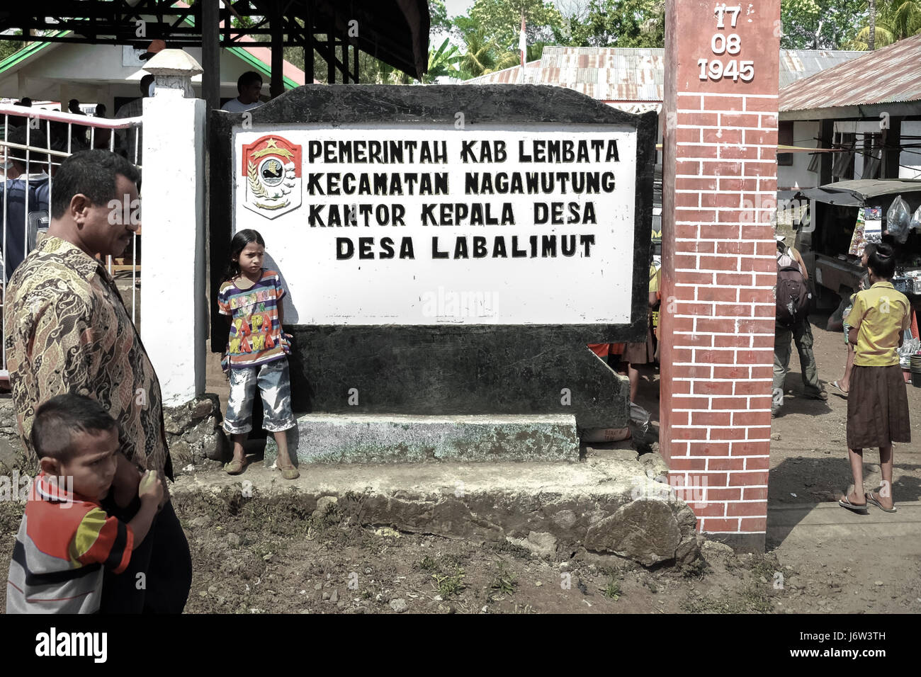 A young girl stands on a sign board of village administration office in ...