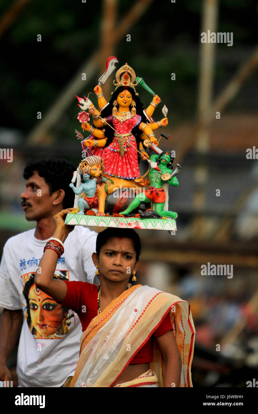 A Hiindu devotee carries the idol of Goddess Durga to Bina Smriti Ghat ...