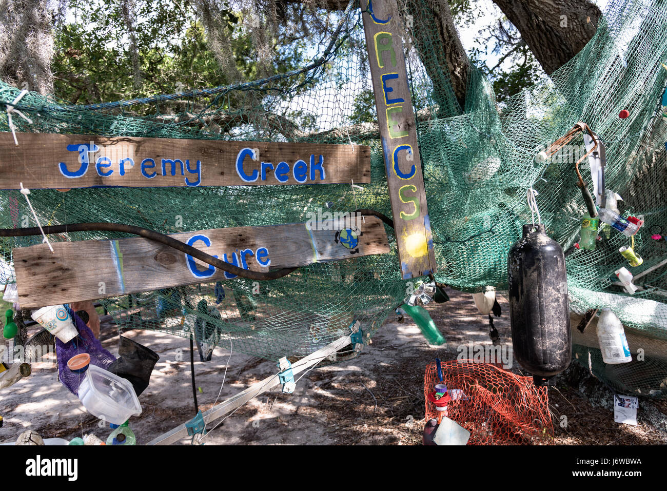 A sculpture made from waste and trash washed up in Jeremy Creek hangs ...