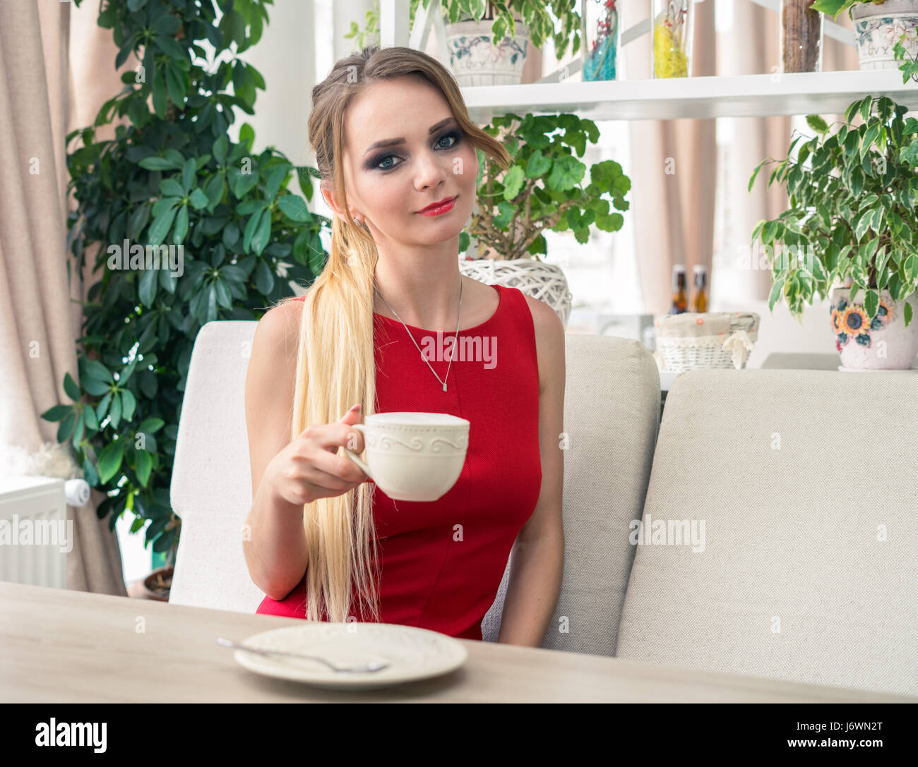 Businesswoman drinking coffee or tea at the restaurant. Lady in red ...