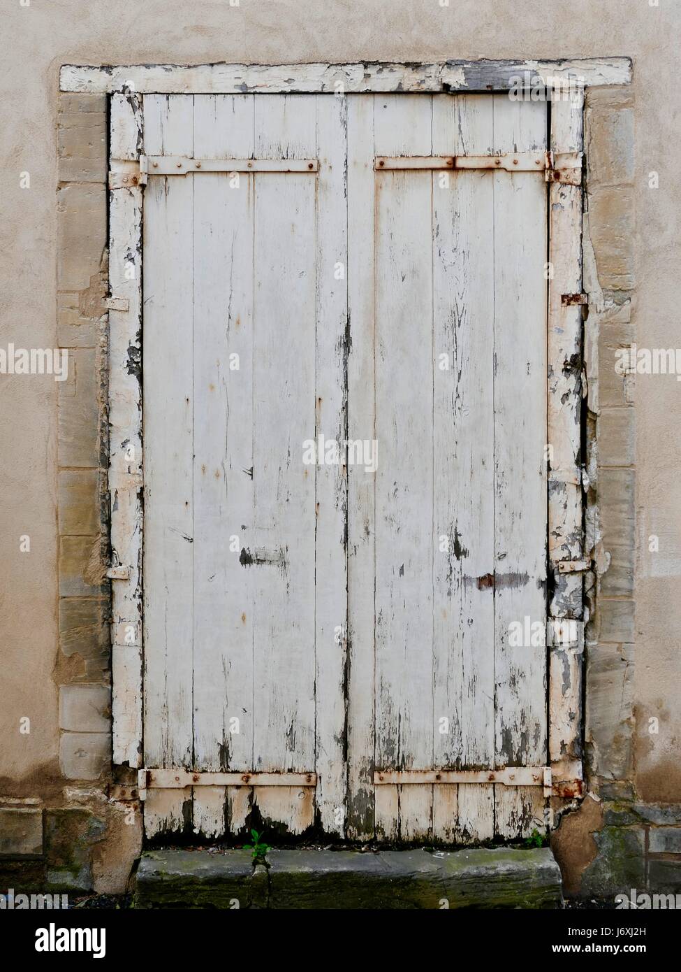 Old, white, wooden, double door with rotted edges. Rusty metal. Off ...