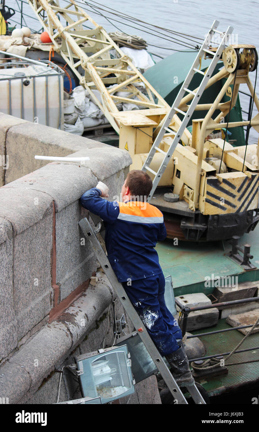 The worker mason repairs the seams between the granite slabs on the ...
