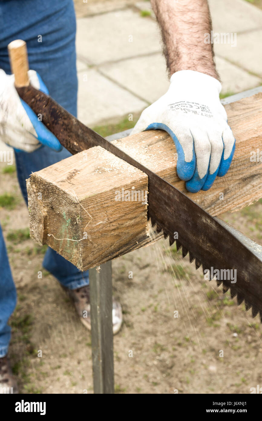 A construction worker cuts a hand saw on a piece of raw wood Stock ...