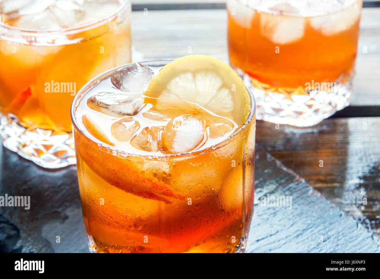 Iced tea with lemon and peach slices and ice cubes on slate and wooden ...