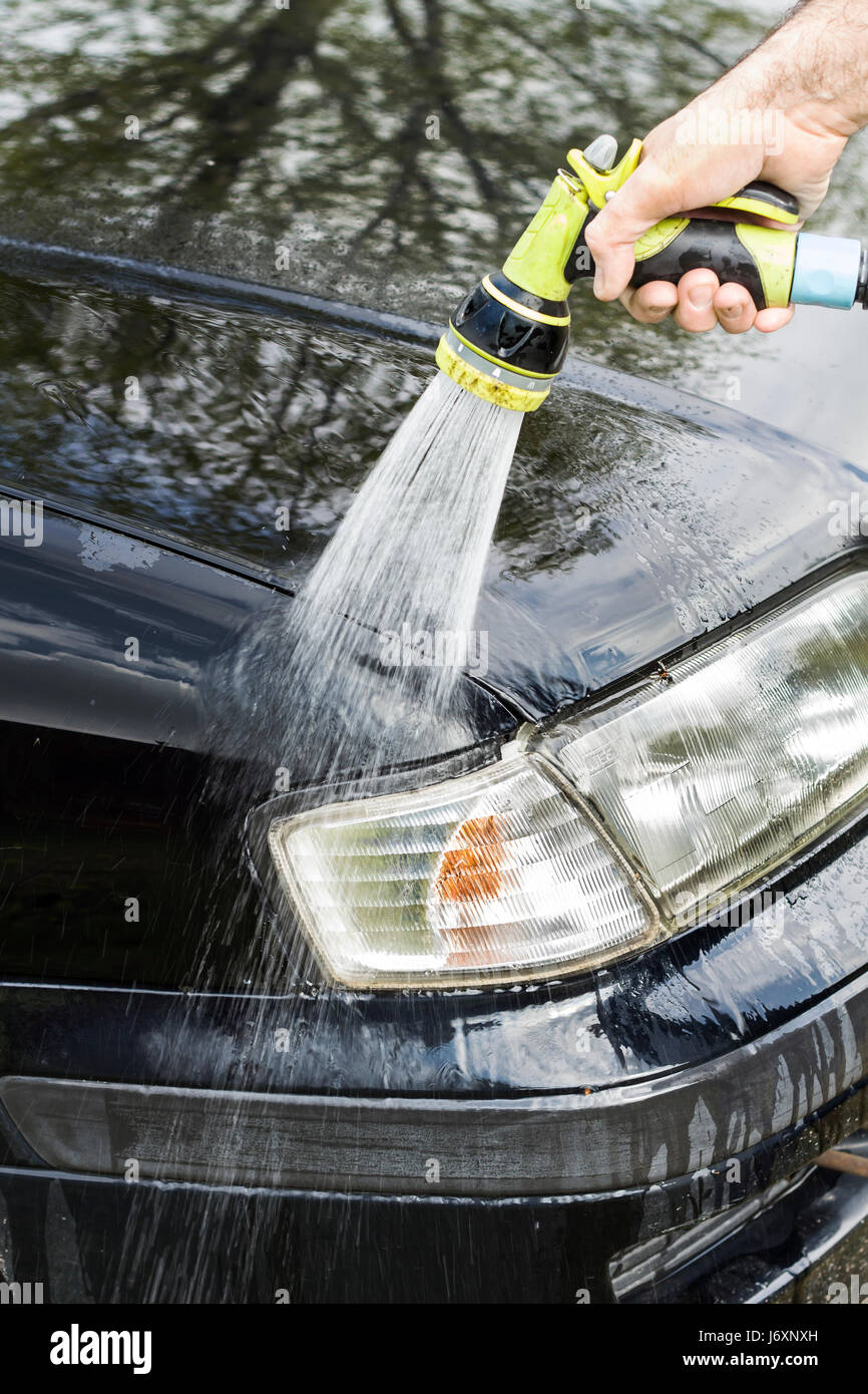 Washing the car. Man rinses the car's mask holding the garden hose ...