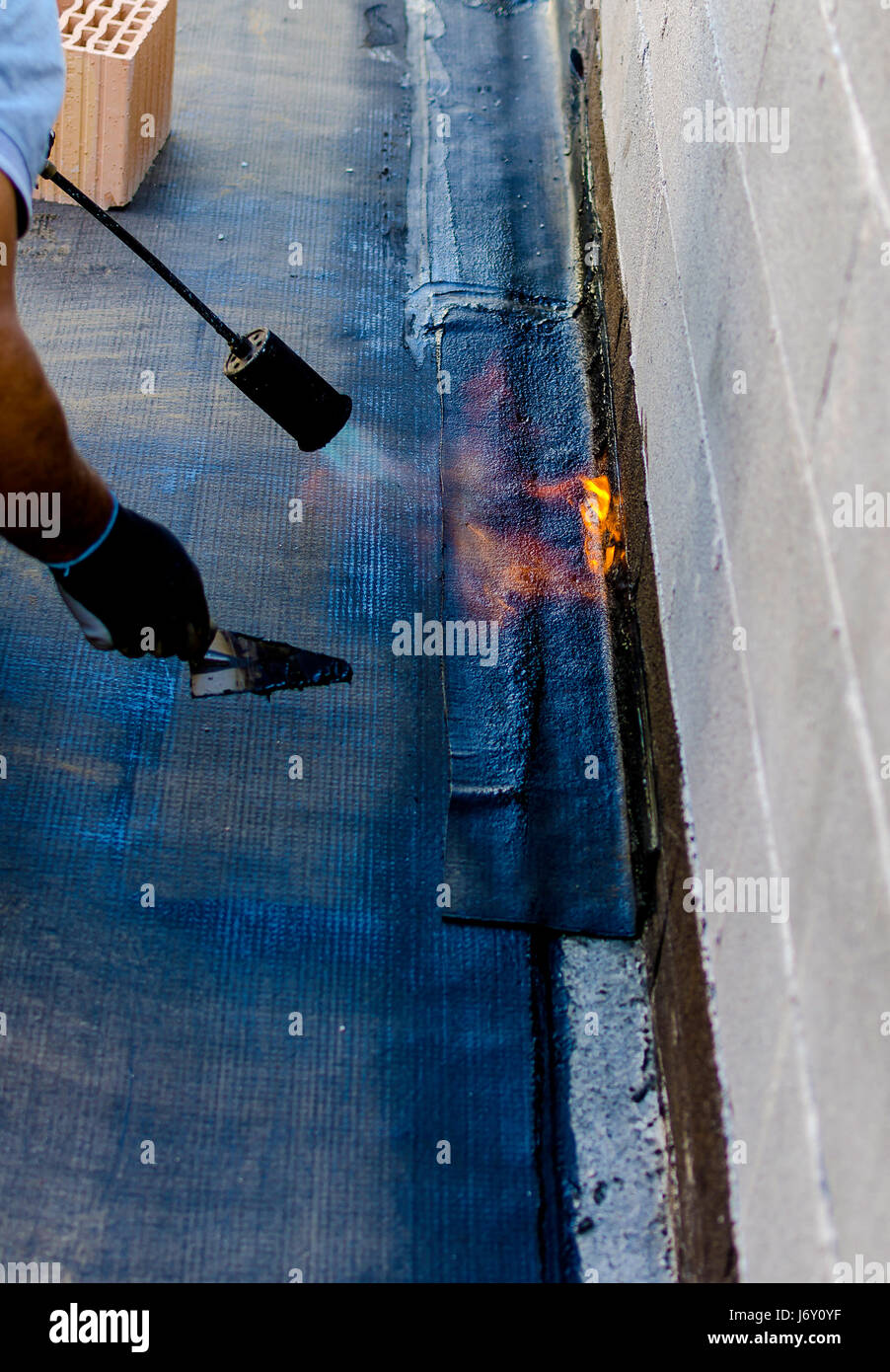 Roofer installing rolls of bituminous waterproofing membrane for the ...