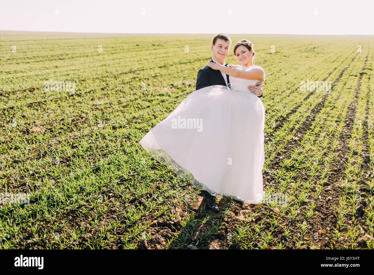 The full-length view of the groom carrying the bride at the background ...