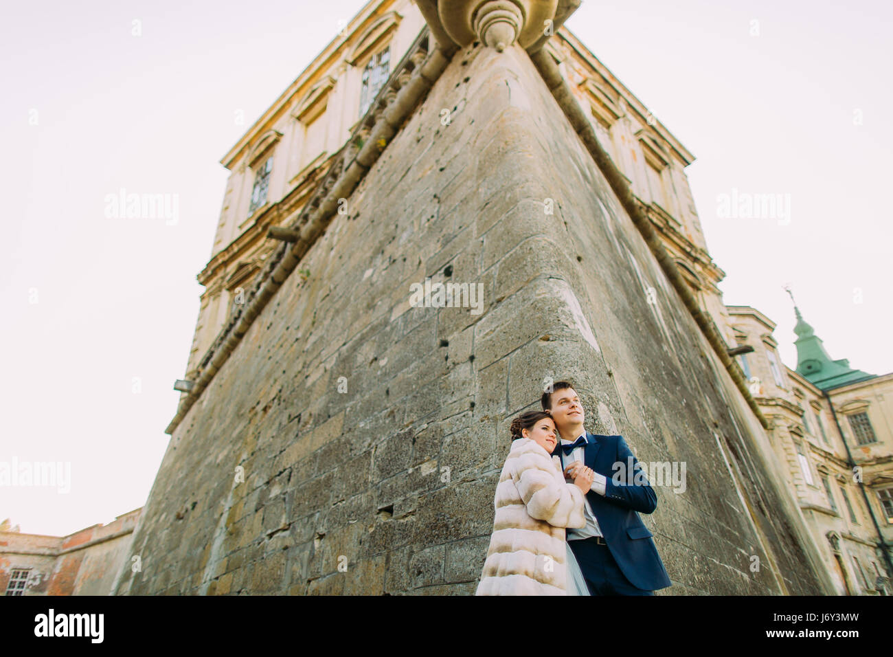 Down side view of the hugging newlyweds leaning on the walls of the ...