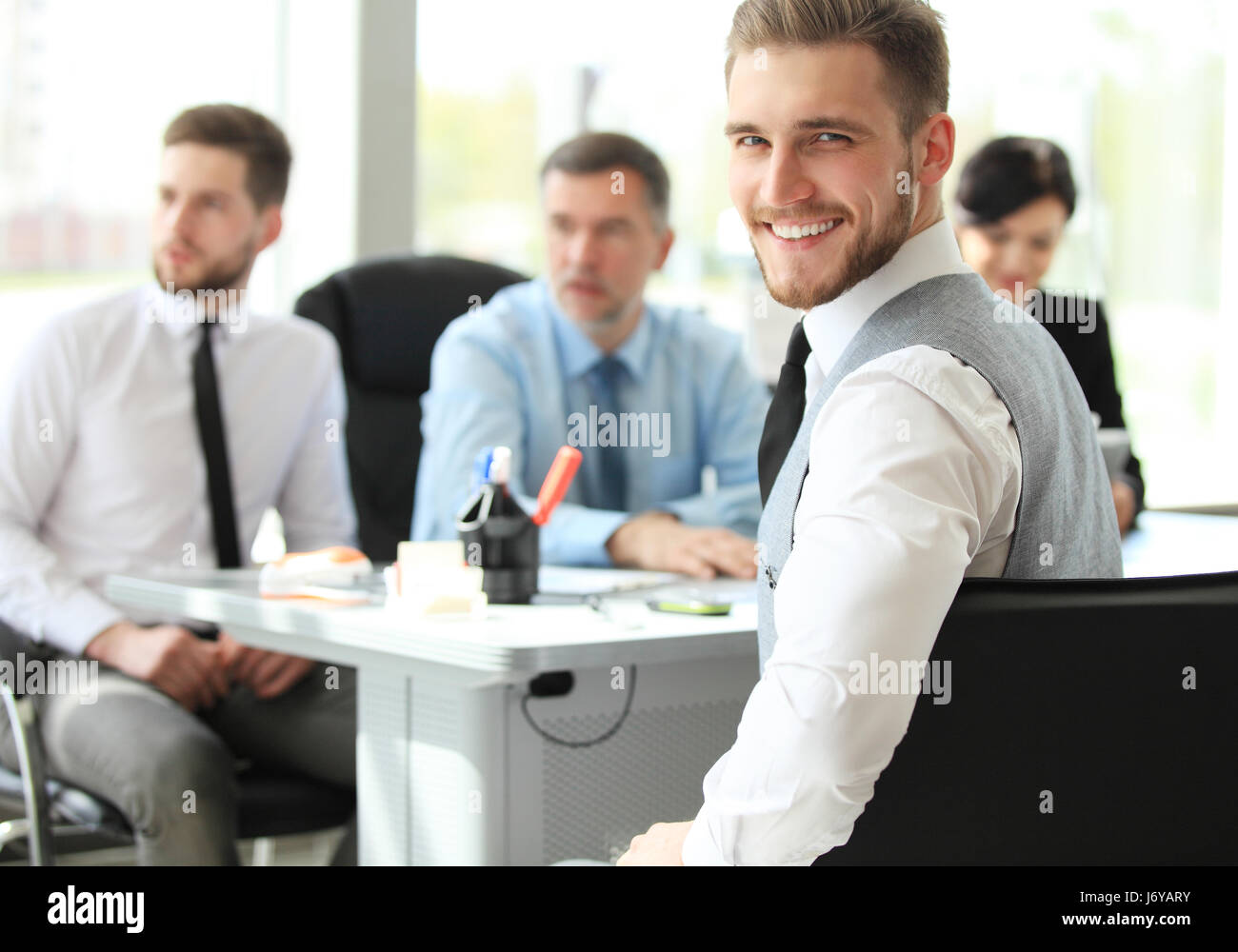 Happy smart business man with team mates discussing in the background ...