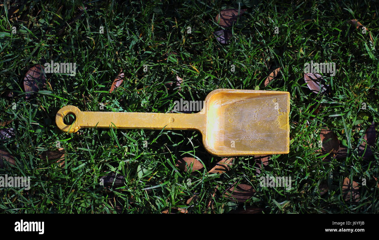 An abandoned and faded yellow child's toy spade Stock Photo - Alamy