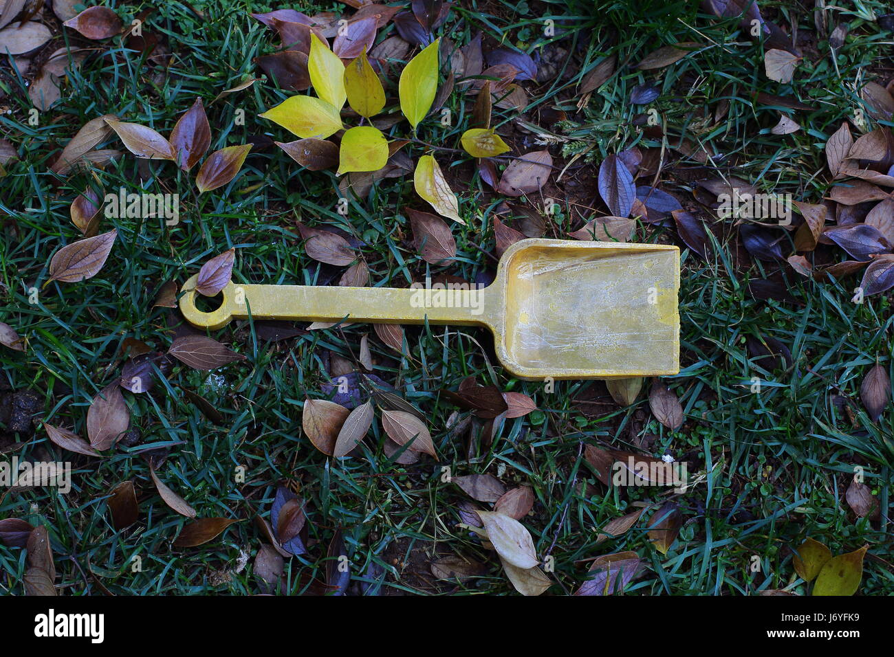 An abandoned and faded yellow child's toy spade Stock Photo - Alamy