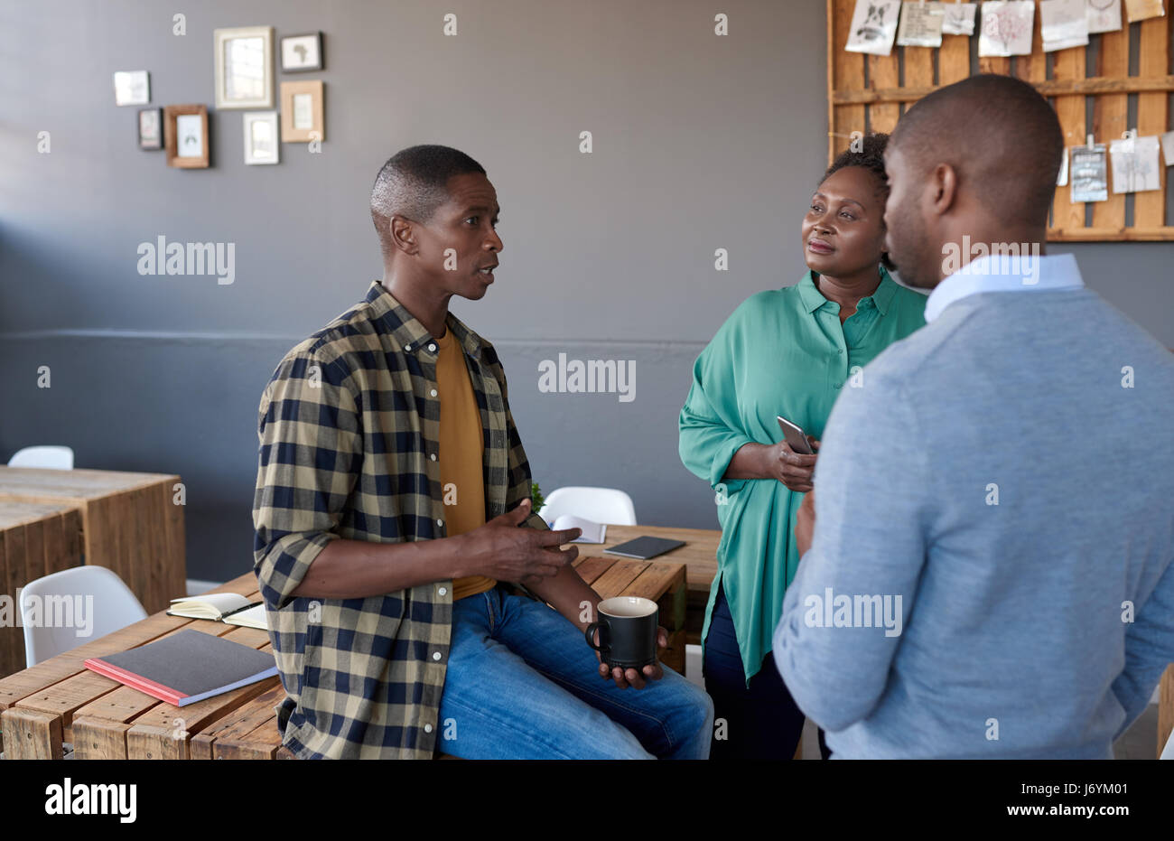 Three African coworkers talking together during an office coffee break ...