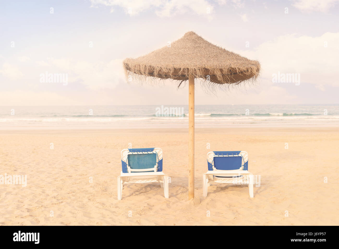 Two sun loungers and a parasol on beach Stock Photo - Alamy