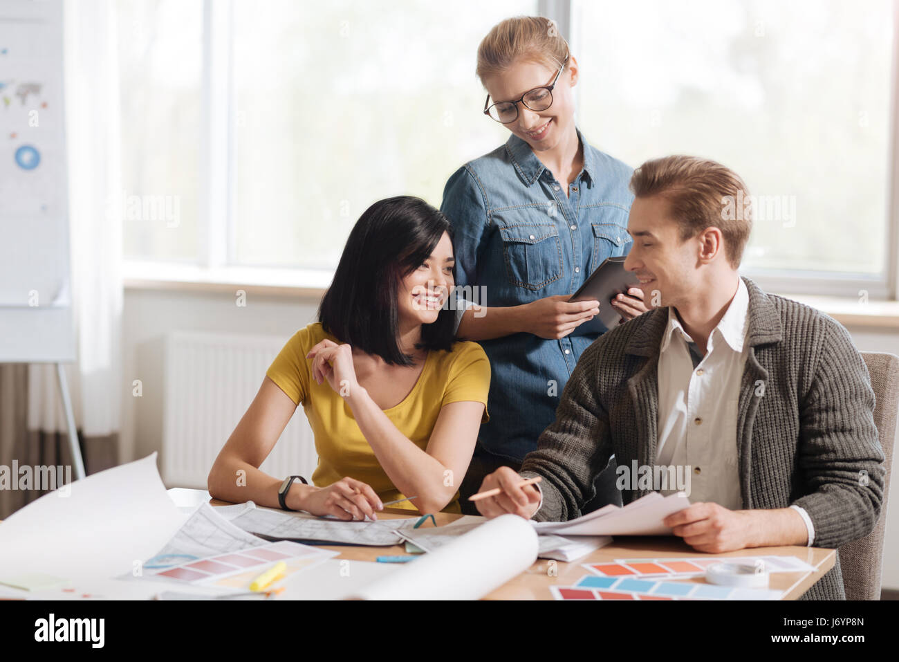 Happy hard working designers talking to each other Stock Photo - Alamy