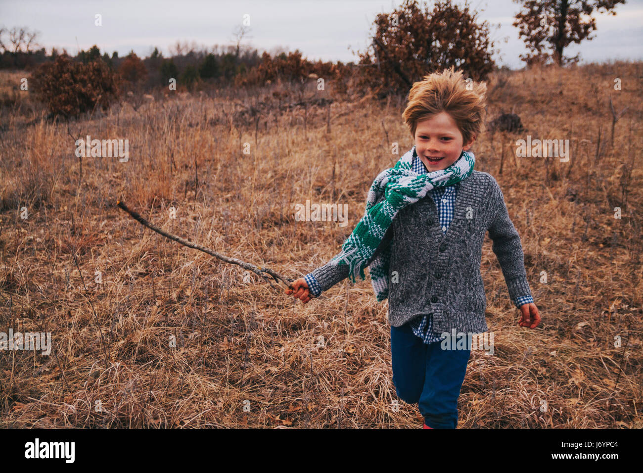 Boy running through rural landscape holding a stick Stock Photo - Alamy