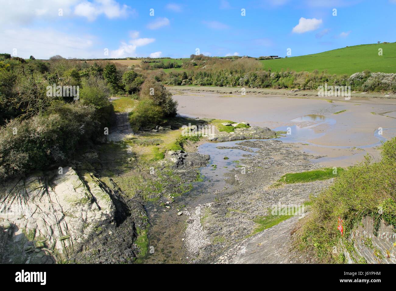 Part of the Camel Estuary in Cornwall at low tide with green fields and ...