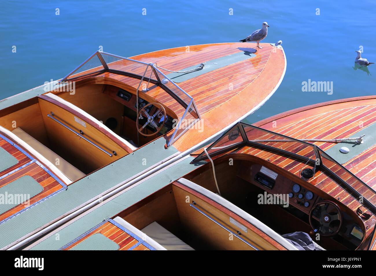 Two classic wooden speedboats moored in blue water ready to take ...