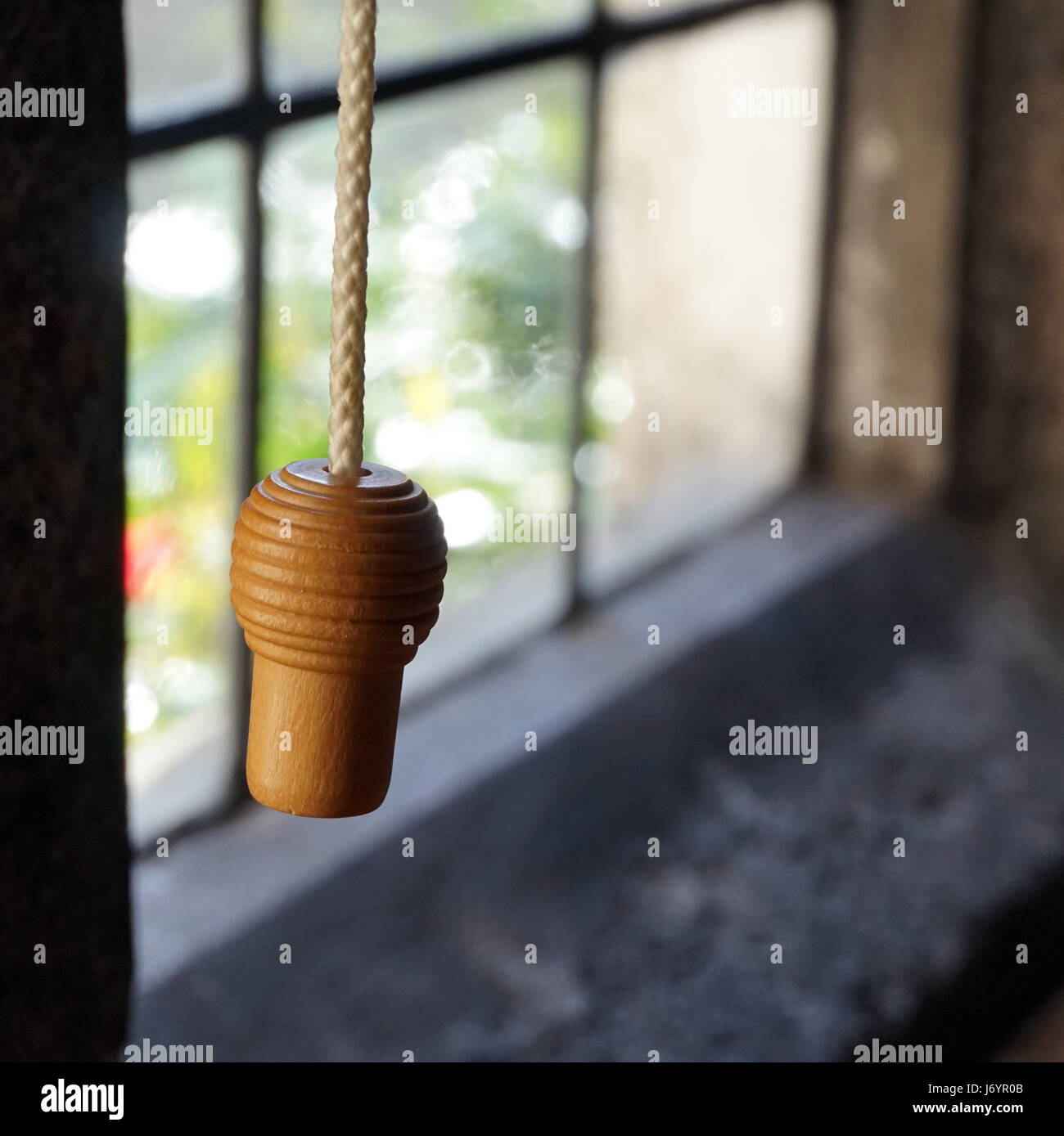 Wooden knob or handle on a curtain pull cord in an old stone window ...