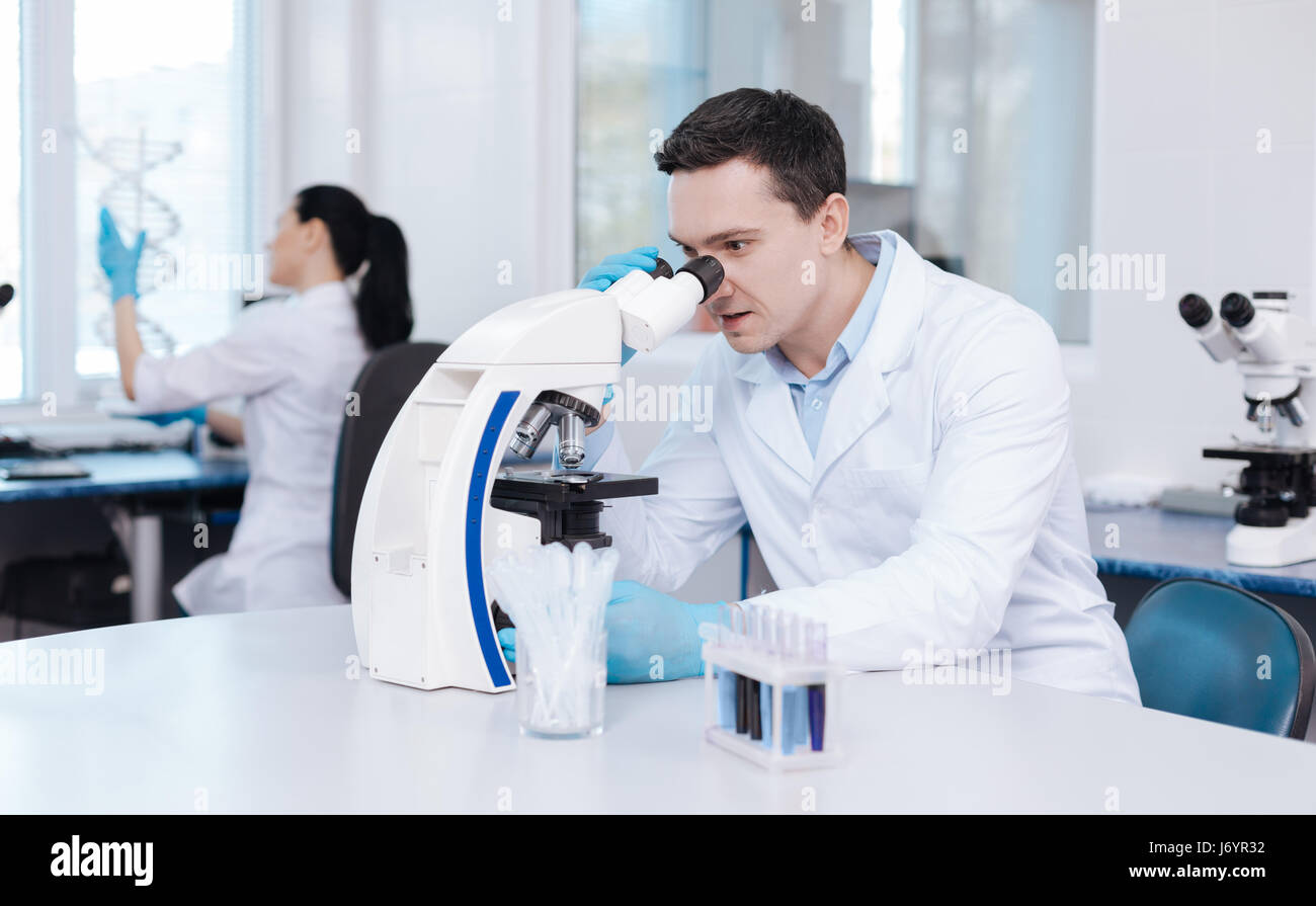 Handsome brunette looking into microscope Stock Photo - Alamy