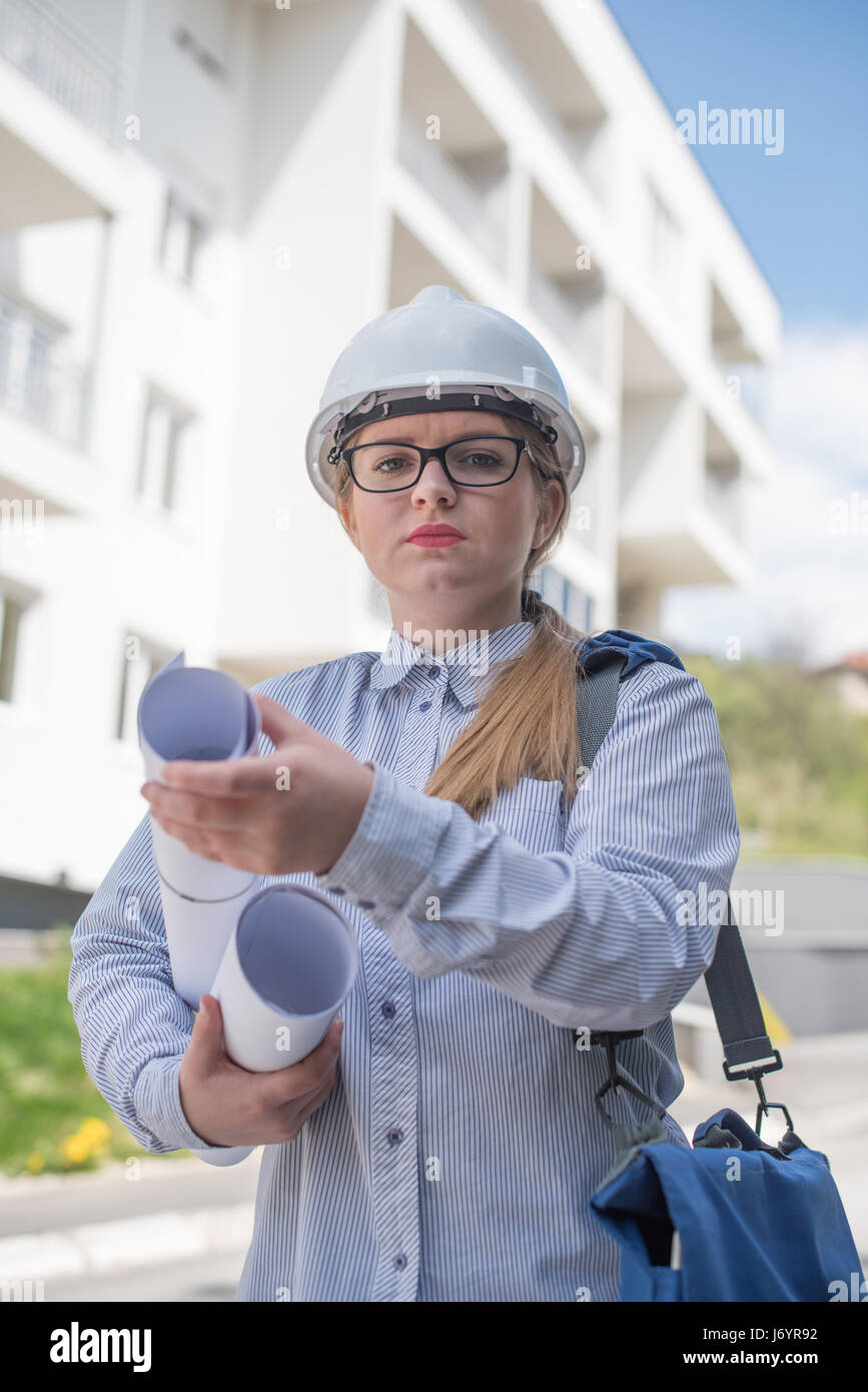 Portrait of an engineer standing in front of building holding ...