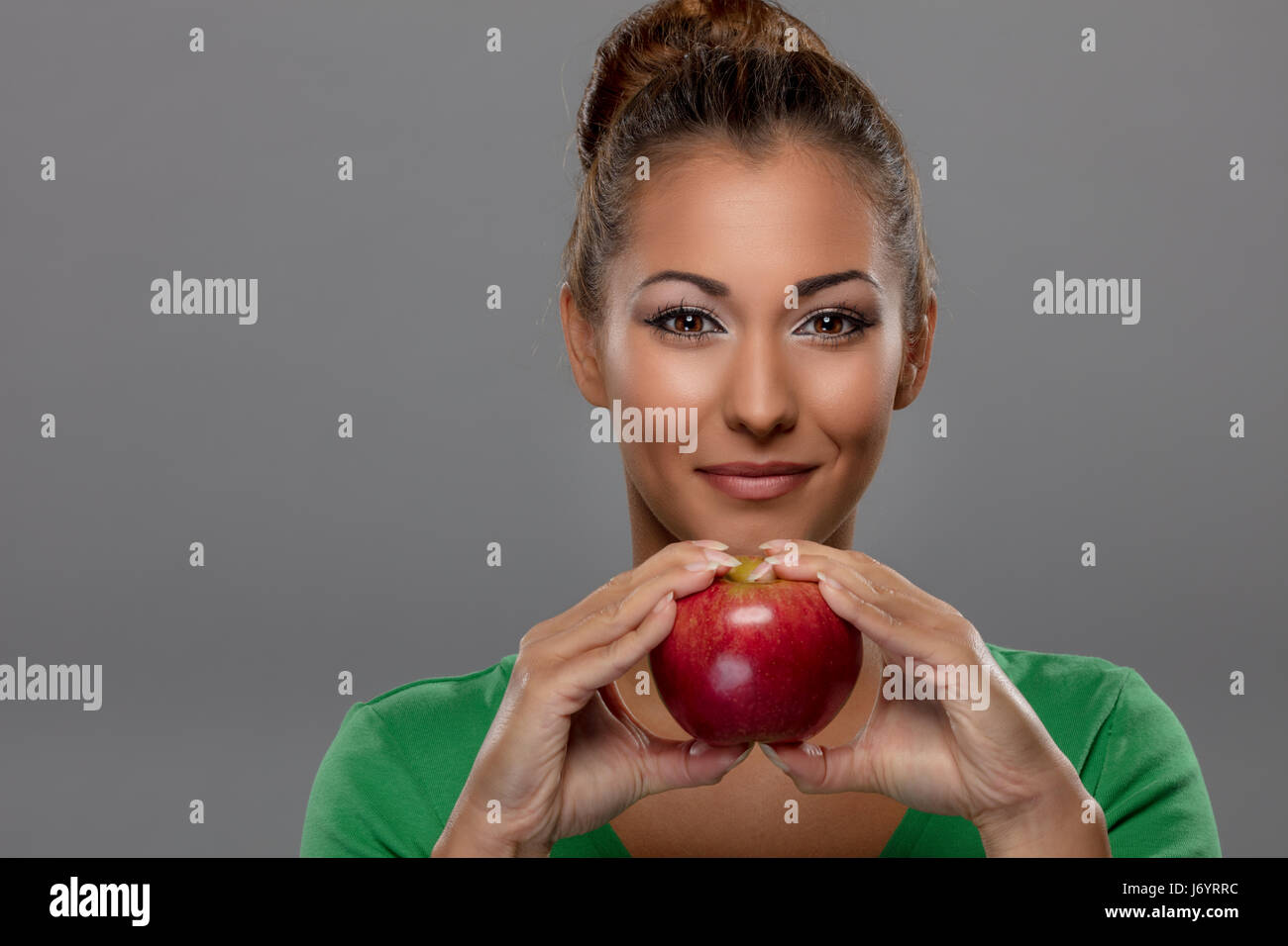 Beautiful young smiling woman holding red apple. Looking at camera ...