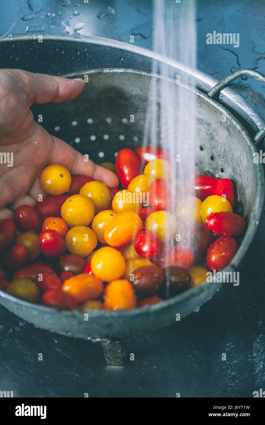 Man's hand washing cherry tomatoes in colander Stock Photo - Alamy