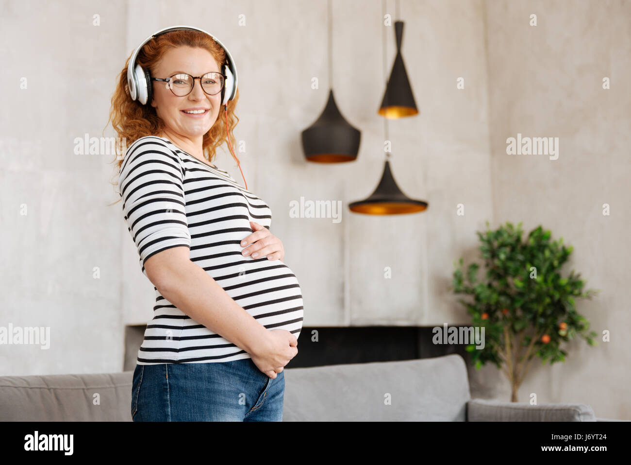 Smiling preggy woman posing with baby bump Stock Photo - Alamy