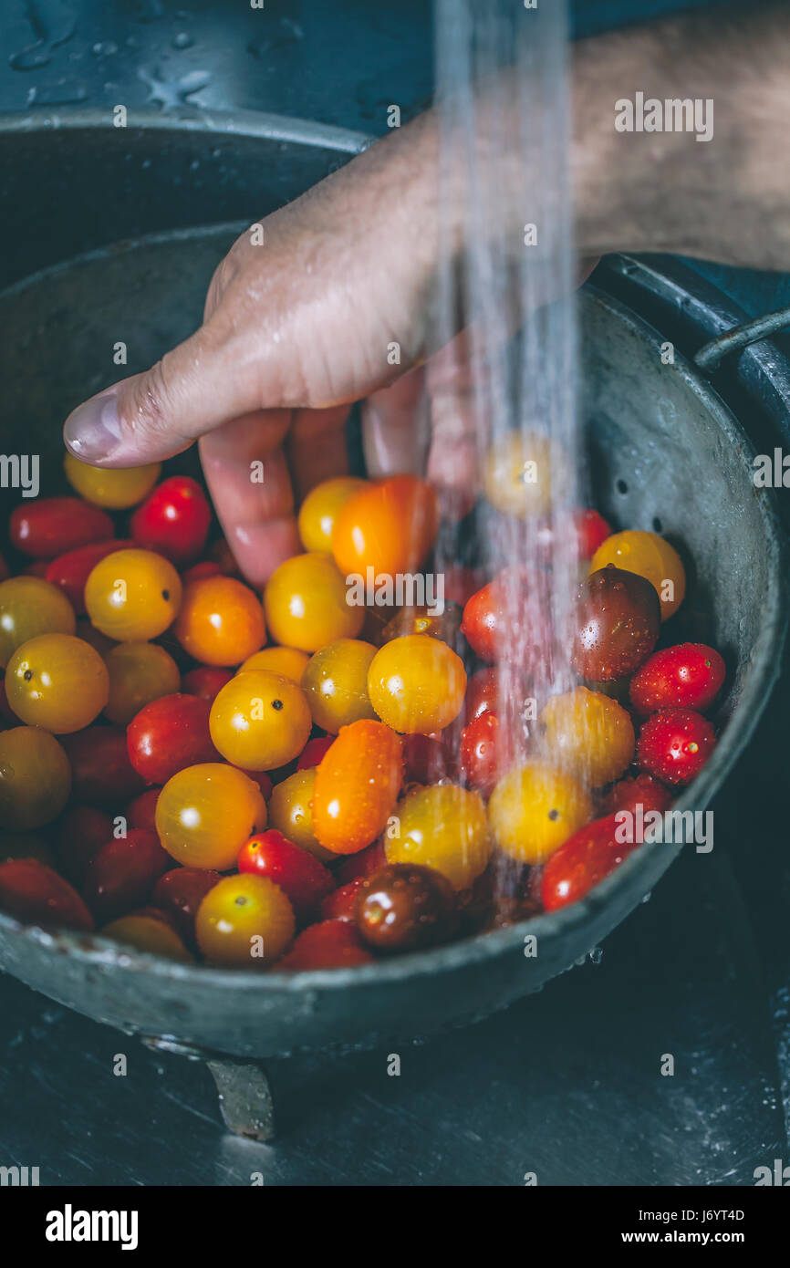 Man's hand washing cherry tomatoes in colander Stock Photo - Alamy