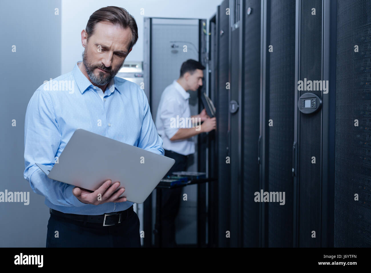Nice serious programmer looking at the laptop screen Stock Photo - Alamy
