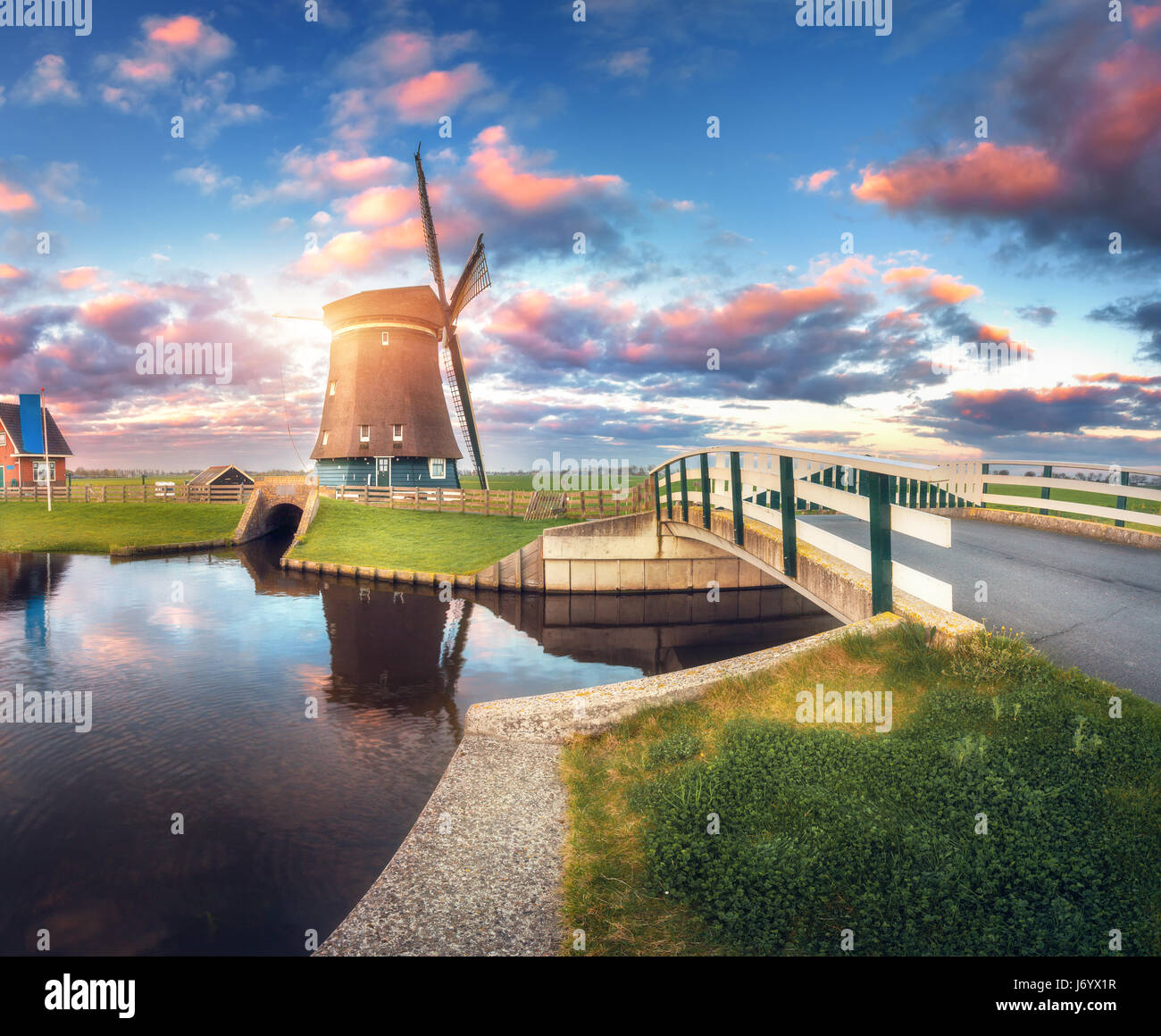 Windmill and bridge near the water canal at sunrise in Netherlands ...