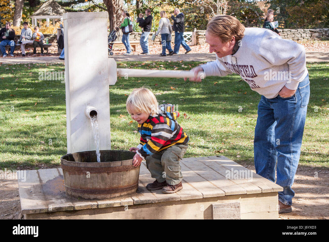 Man pumping water at Old Sturbridge Village with a grandchild looking ...