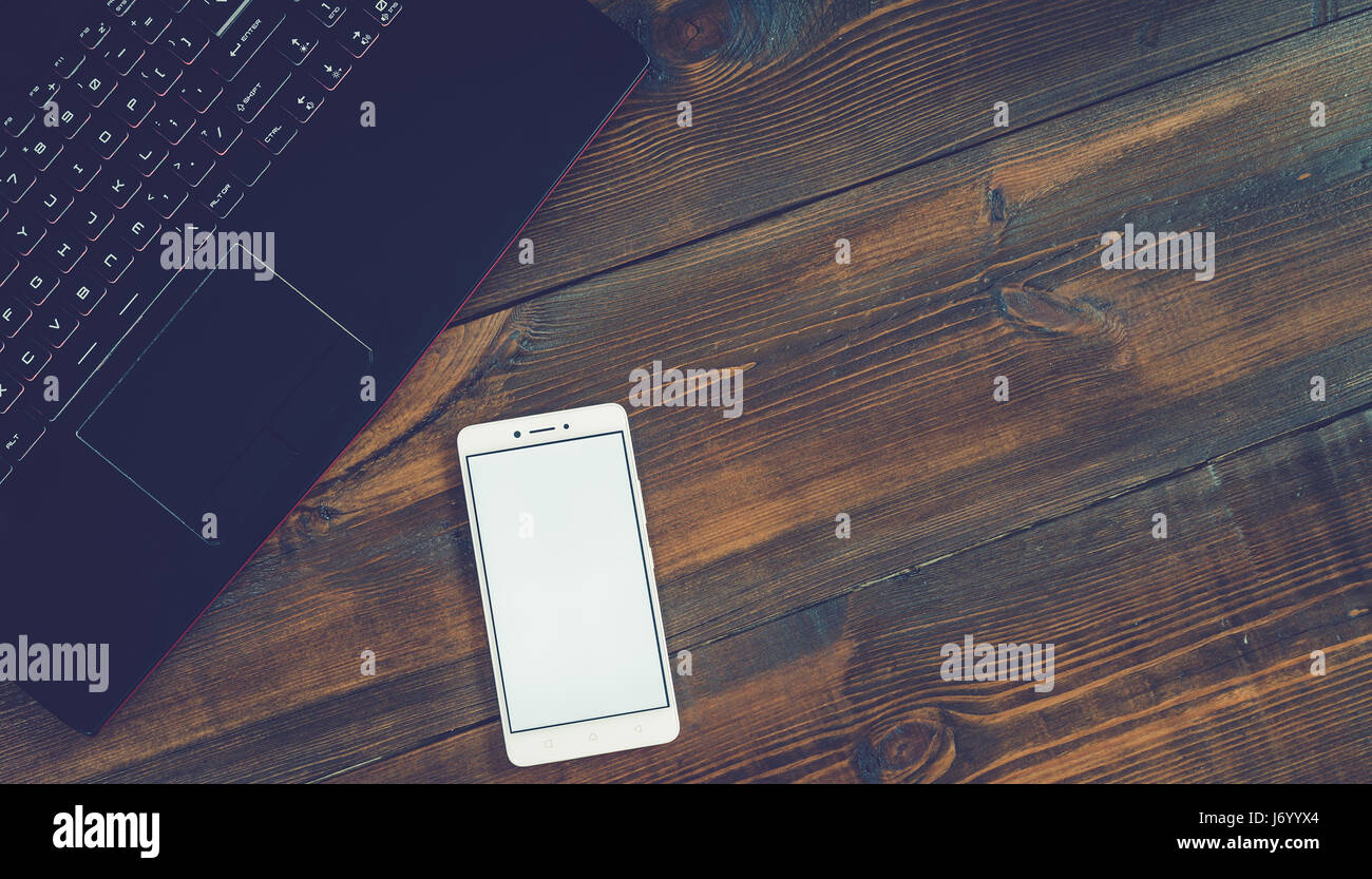 Workspace with laptop and smartphone on hard wood desk Stock Photo - Alamy