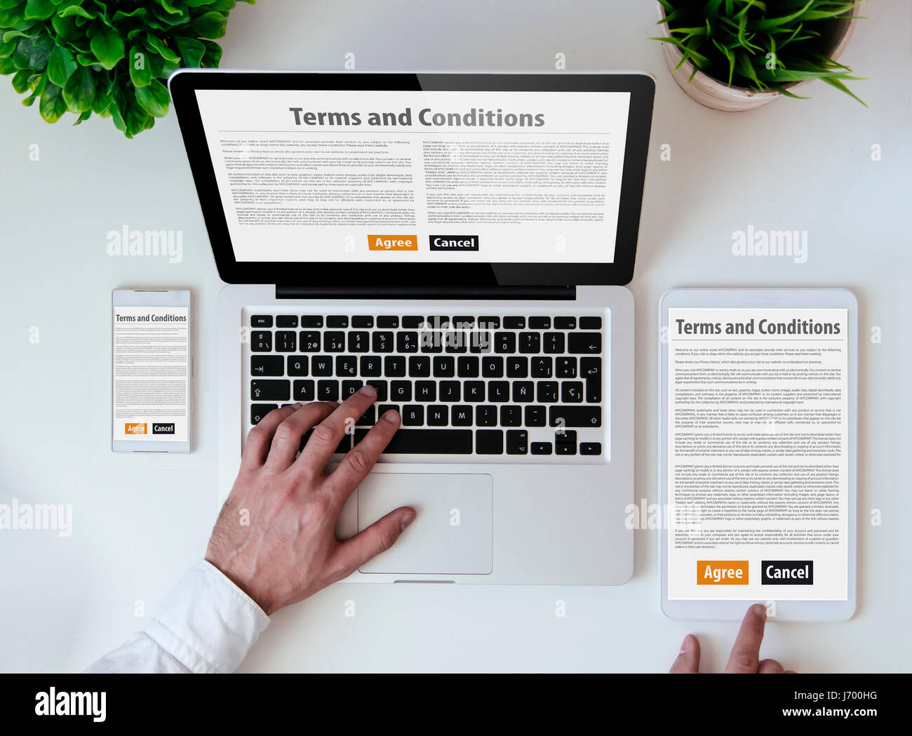 office tabletop with tablet, smartphone and laptop showing terms and ...