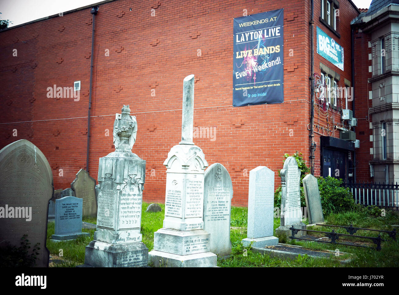 Poster advertising live bands on wall overlooking graves in cemetery ...