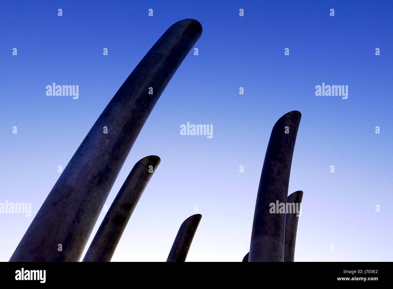 Curved steel pipes against darkenibg blue sky Stock Photo - Alamy