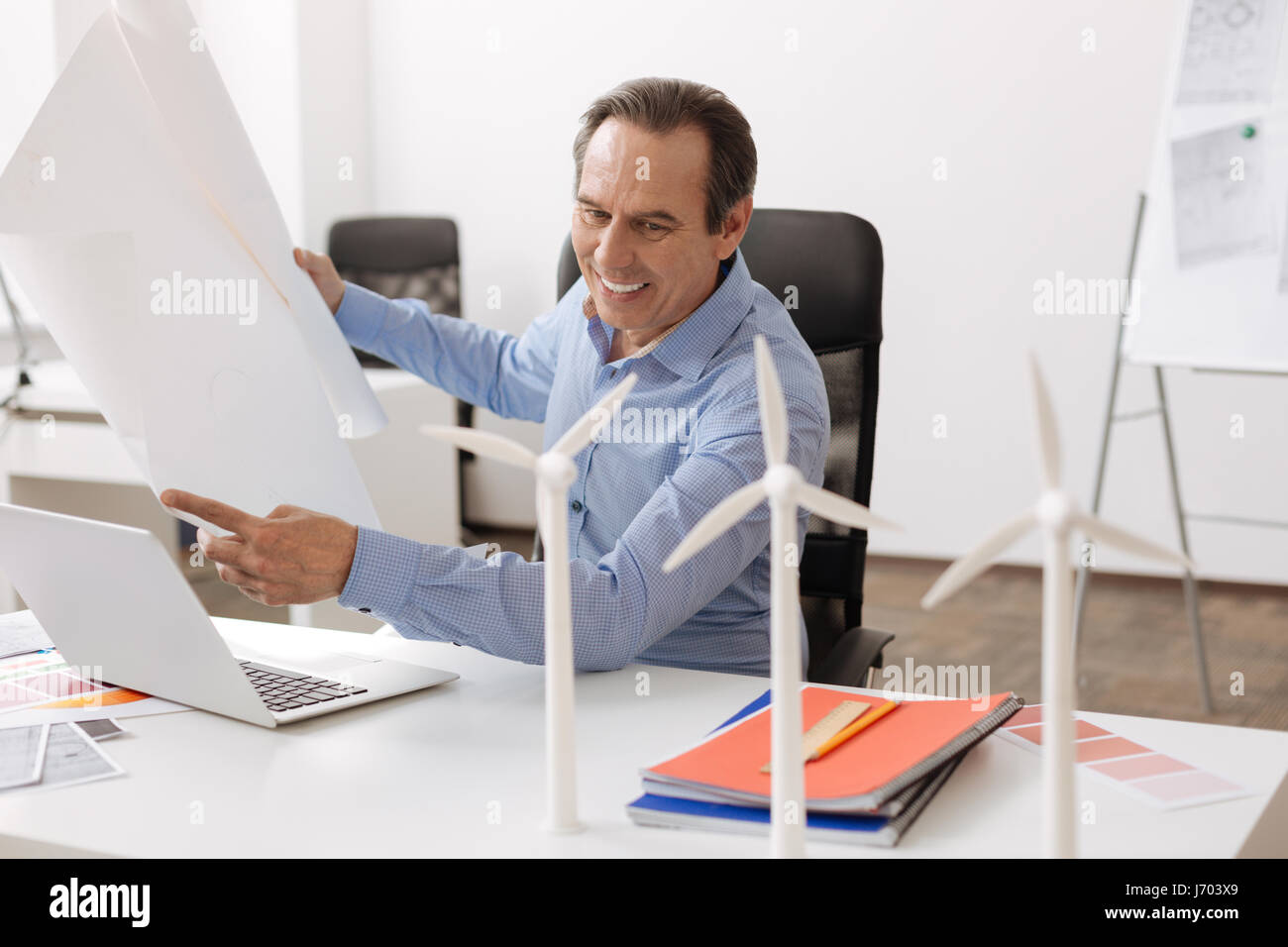 Positive professional engineer working with the blueprint Stock Photo ...