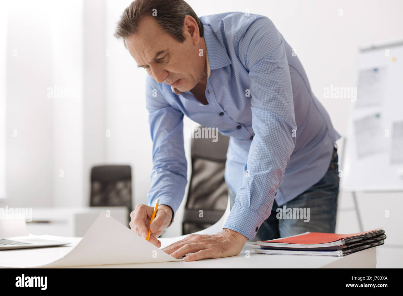 Professional concentrated engineer making changes in the blueprint ...