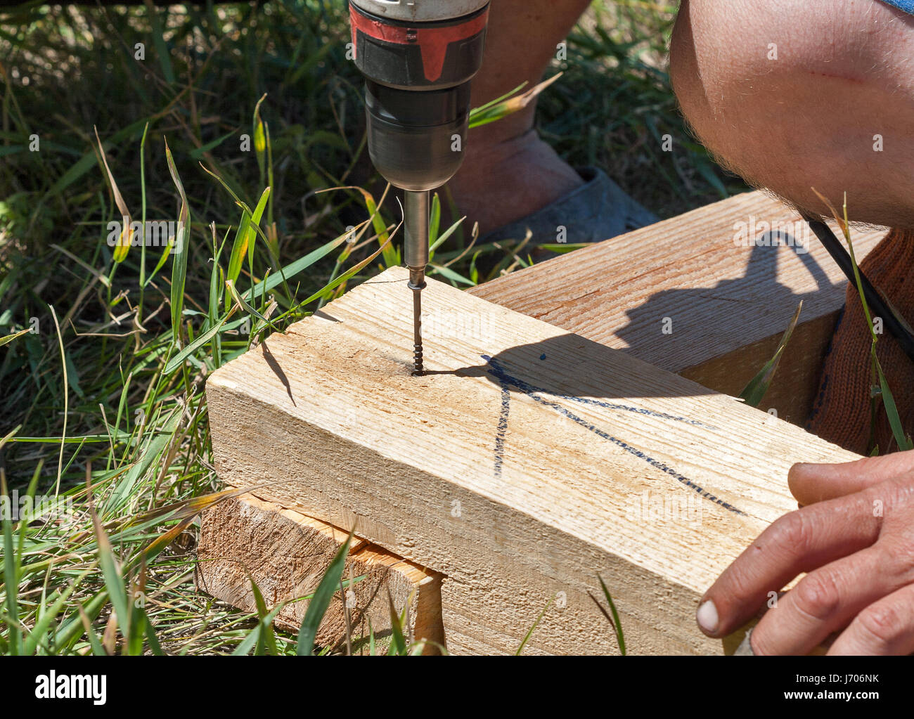 Carpenter using drill and screw on wood at construction site outdoor ...