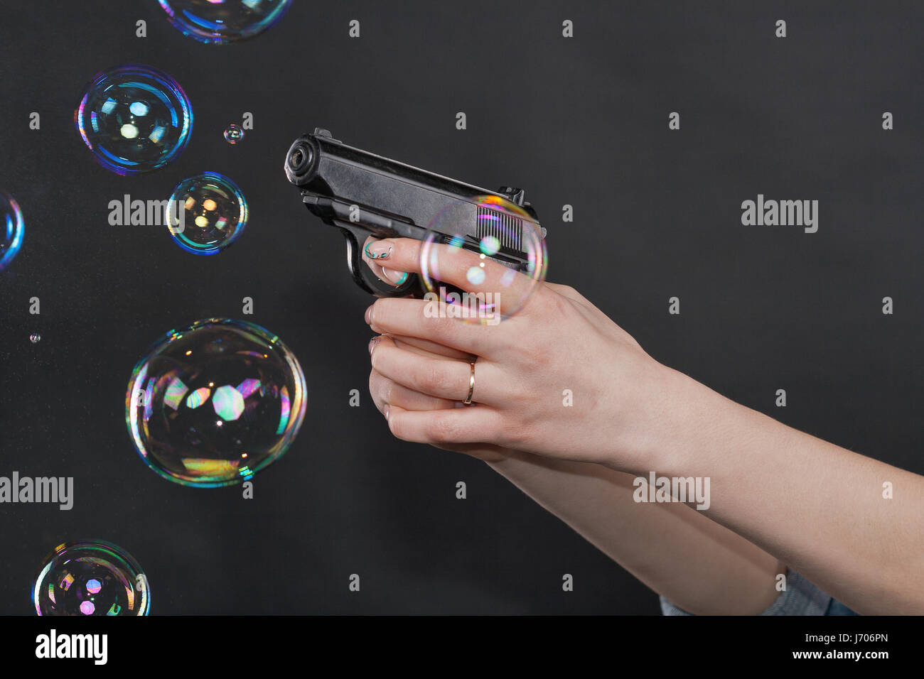 Caucasian women outstretched arms holding a black gun, fingers on the ...